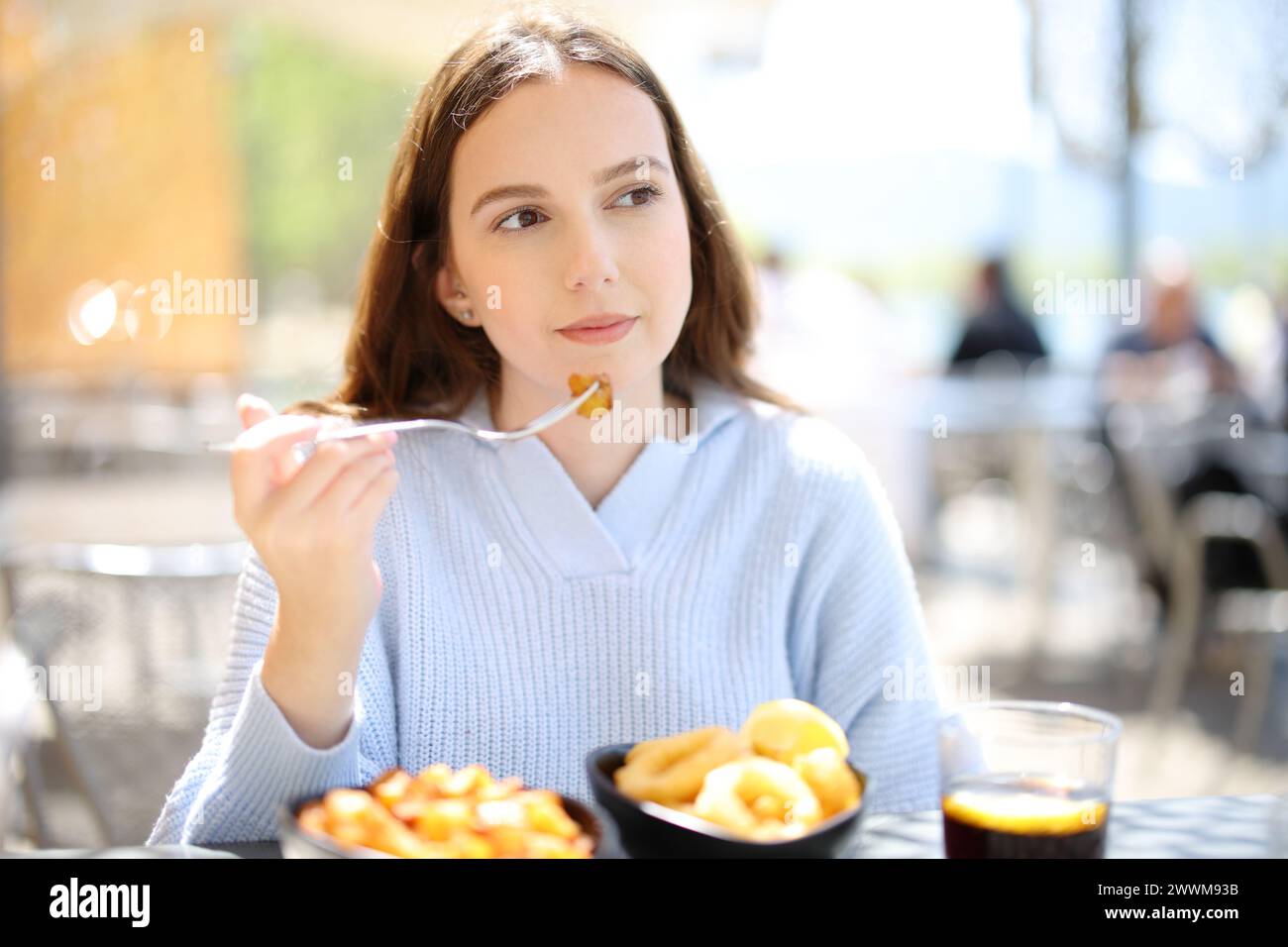 Distracted woman eating tapas in a restaurant terrace Stock Photo - Alamy