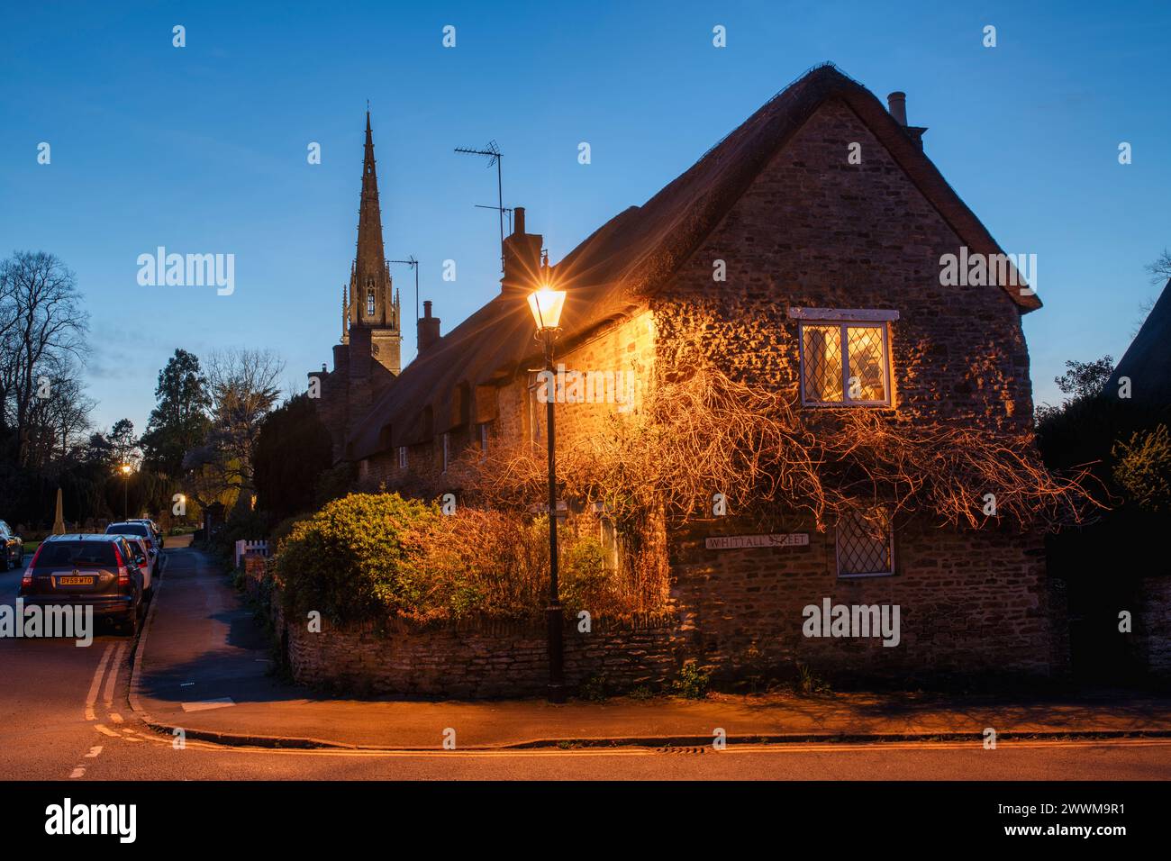 Cottage and church spire lit up at dusk. Kings Sutton, Northamptonshire ...