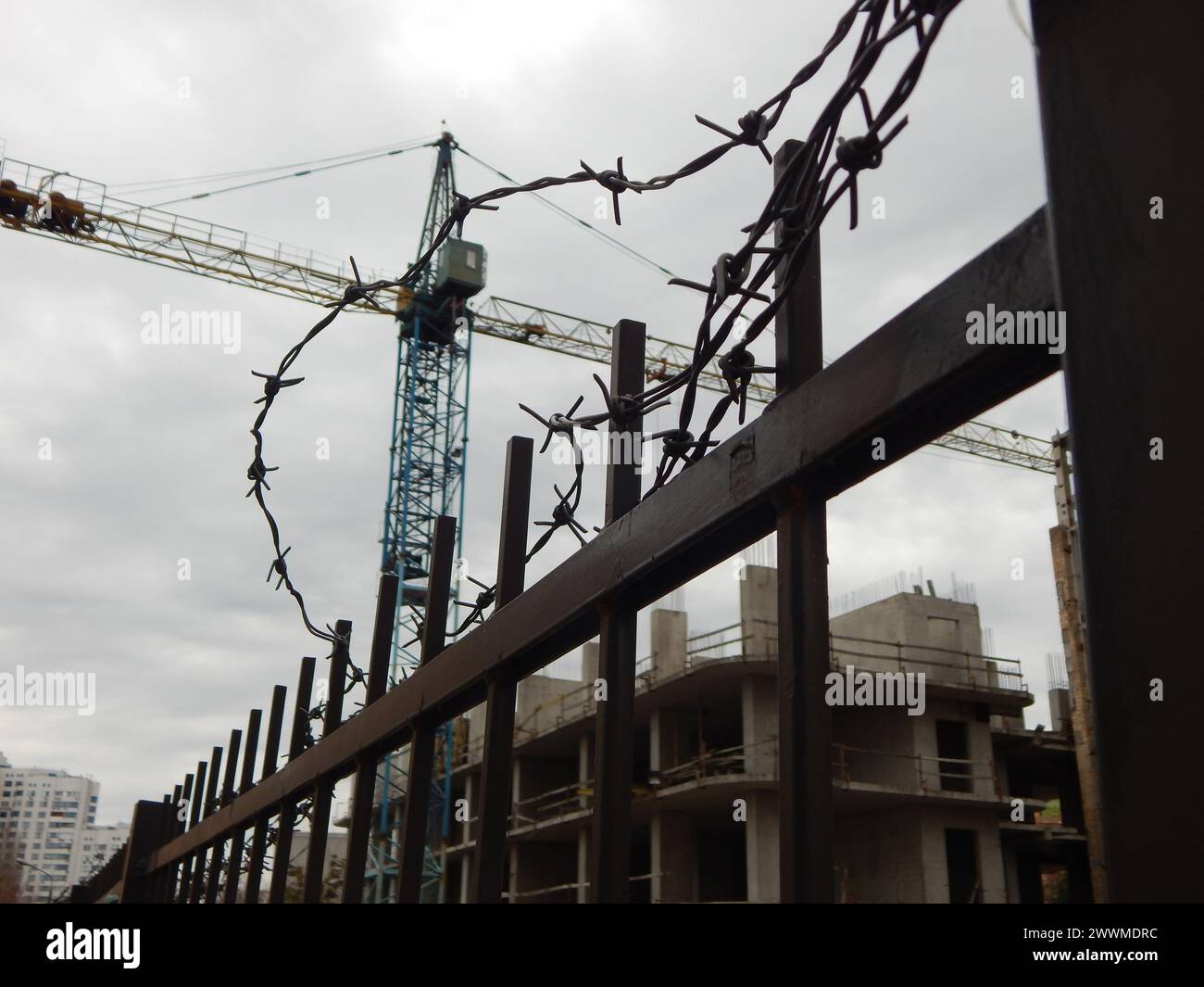 Stopped high-rise construction crane behind a metal fence with barbed ...
