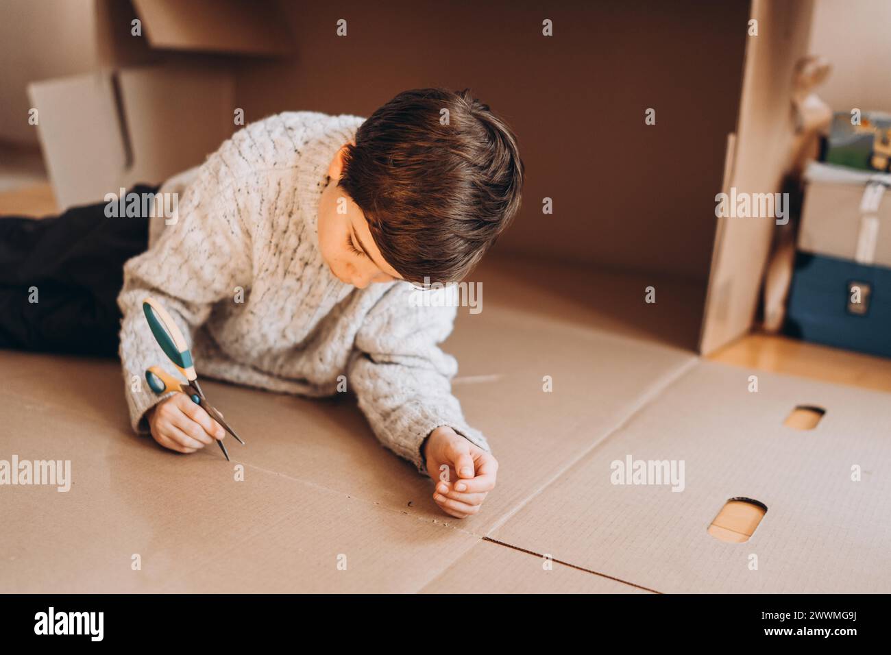 Teenage boy cuts out cardboard with scissors Stock Photo - Alamy