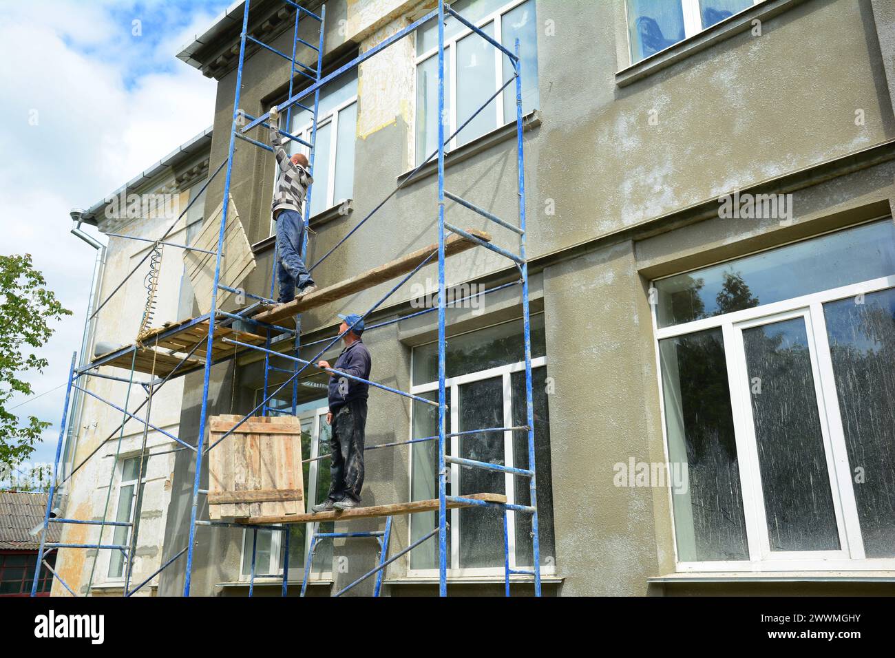 Builder contractors prepare scaffolding for painting house exterior ...