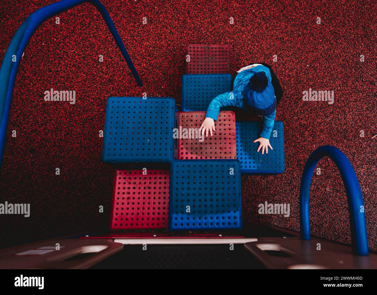 Young boy climbing up red and blue playground steps Stock Photo - Alamy