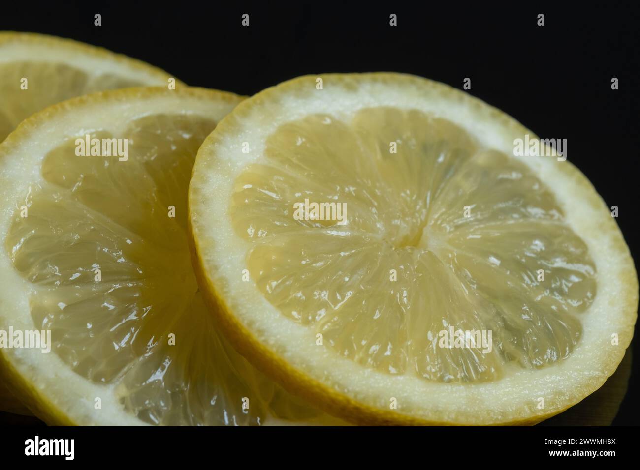 Closeup of sliced lemons against black background Stock Photo - Alamy