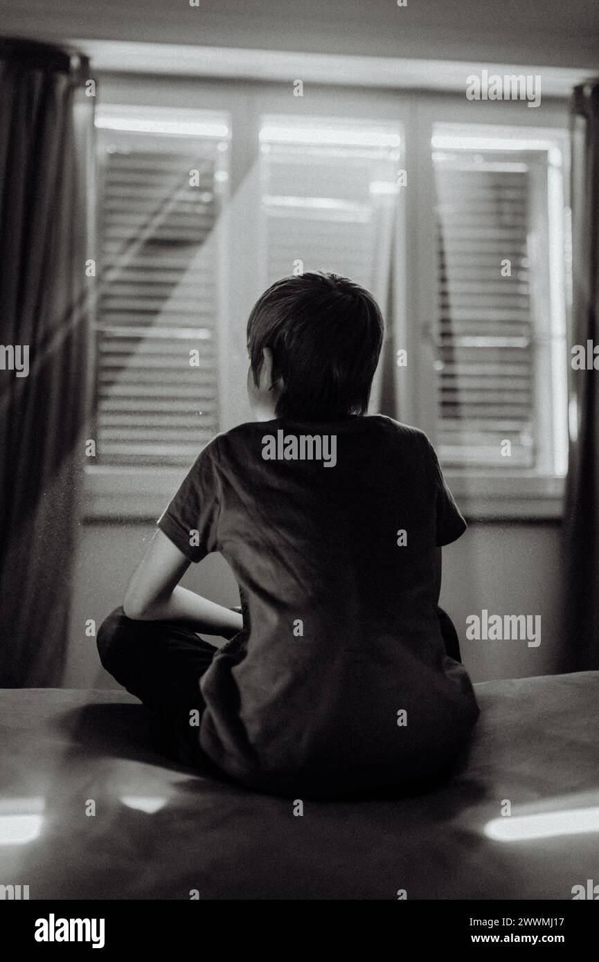 Boy on the bed with light shining through blinds in the pandemic Stock ...
