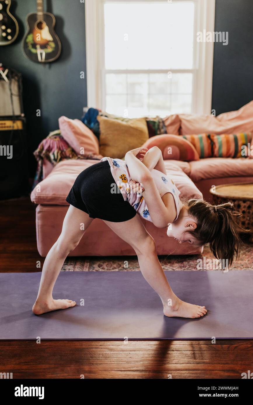 Side view of young girl doing pyramid pose in living room Stock Photo ...