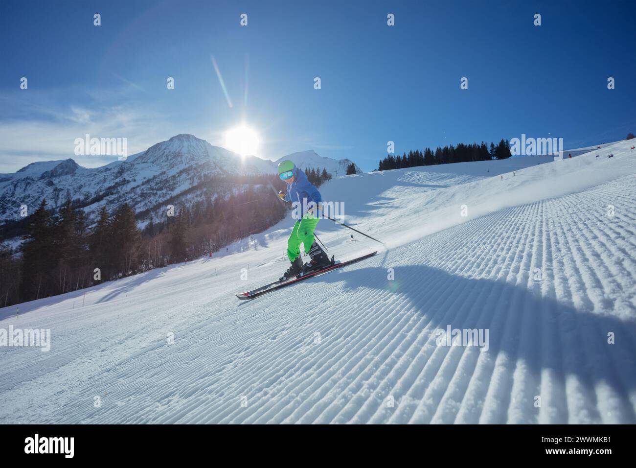 Alpine skier in action glide on a groomed slope with sun flare Stock ...