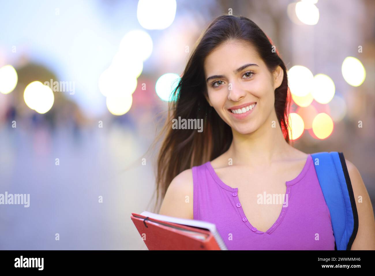 Front view portrait of a happy student posing in the street looking at ...