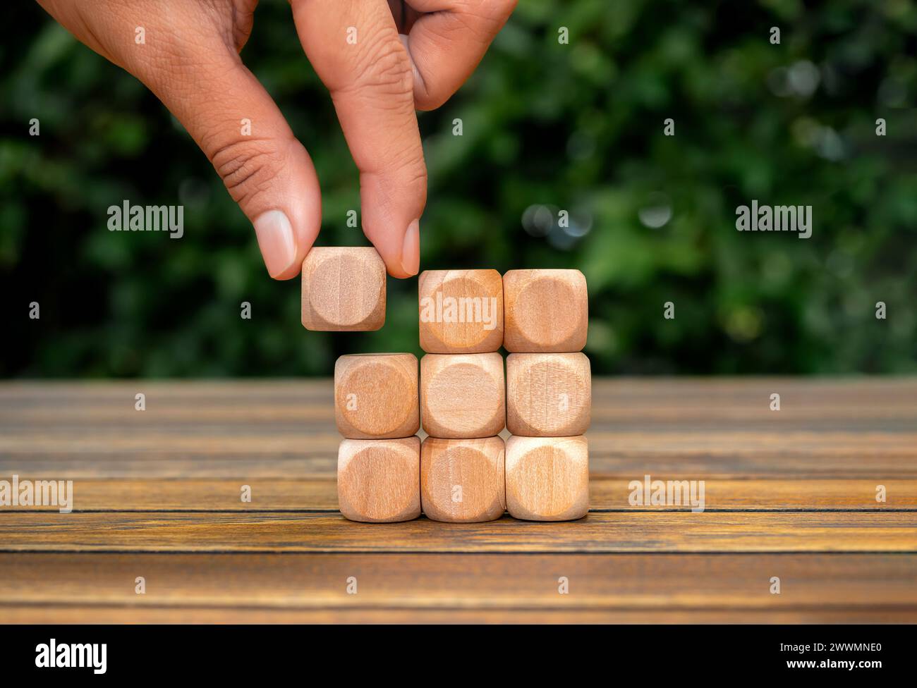 Last piece wood cube block in hand putting on wooden cube as puzzles ...