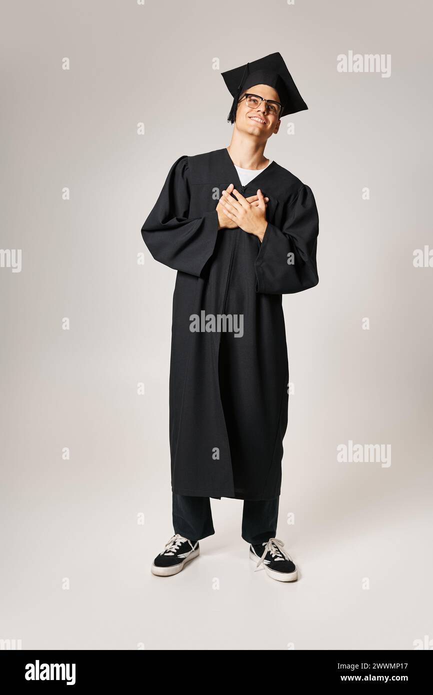 young student in graduate outfit and vision glasses dreaming against ...