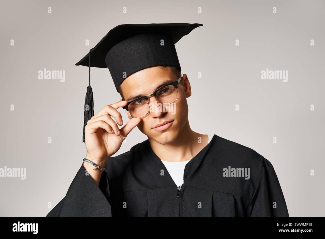 handsome young man in graduate outfit touching hand to vision glasses ...