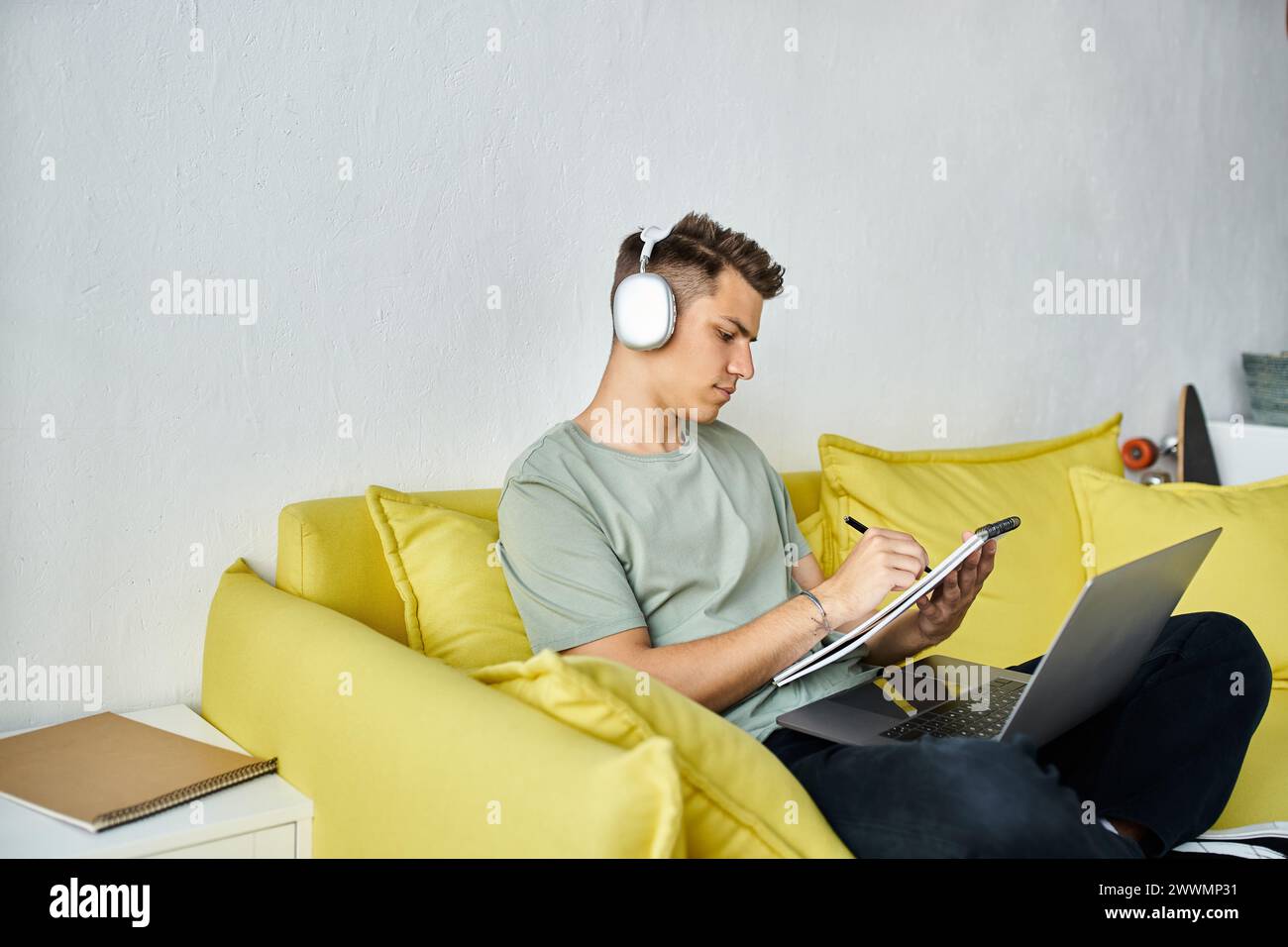 focused student with headphones and laptop in yellow couch studying and ...