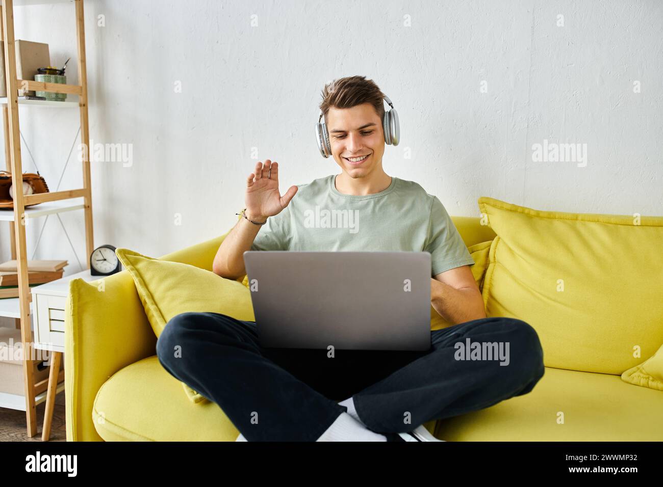 cheerful student with headphones and laptop in yellow couch saying ...