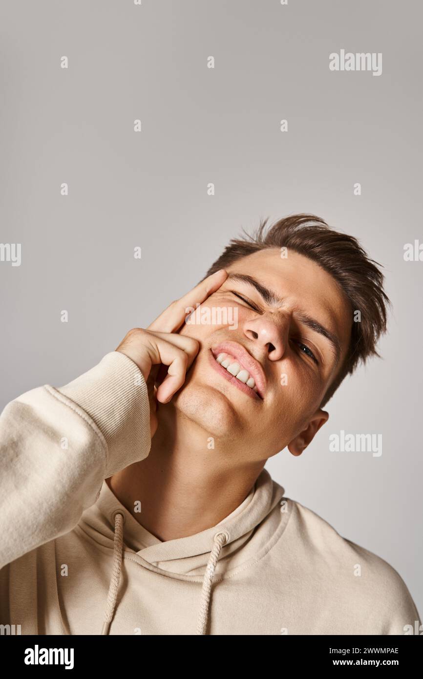 portrait of young guy with brown hair make crooked face with hand ...