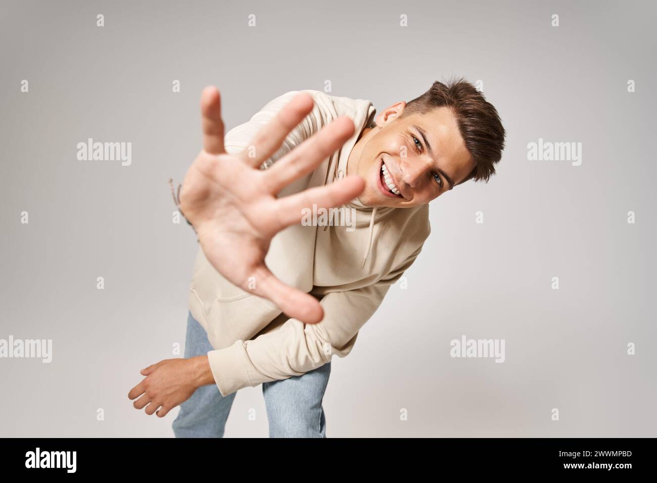 attractive man leaning to forward and holding out his hand to camera ...
