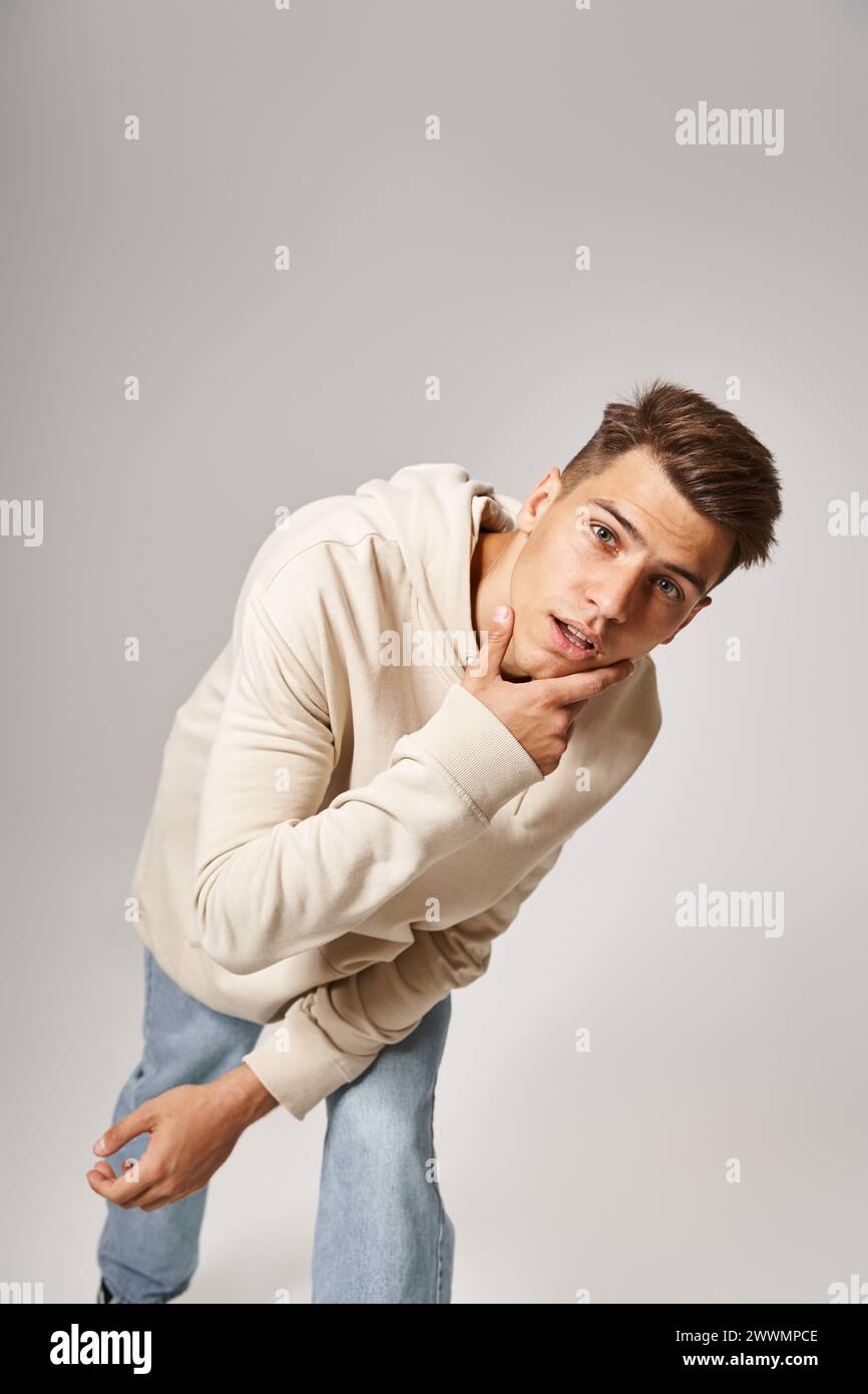 charismatic young guy leaning to forward and touching to jawline ...