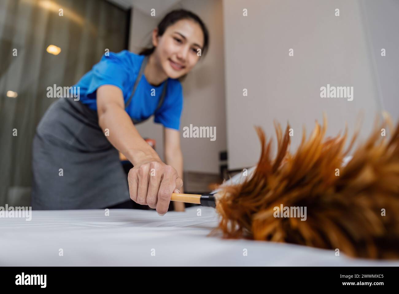 cleaning service woman cleaning dust on bed with feather duster ...