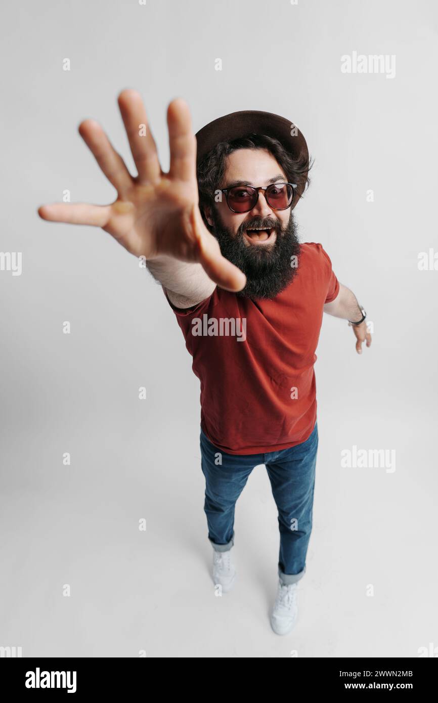Hipster man reaching out in a playful pose on a plain background Stock ...