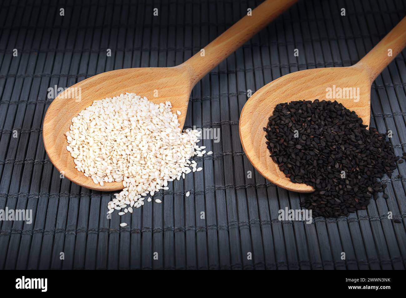 wooden spoons with white and black sesame seeds on a dark bamboo mat ... wooden spoons with white and black sesame seeds on a dark bamboo mat ...