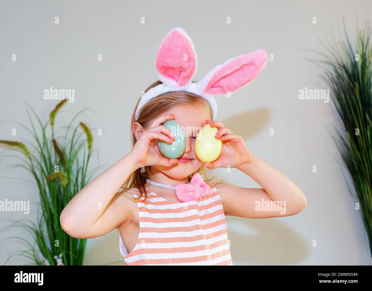 portait of Blond child girl wearing bunny ears on Easter day play with ...