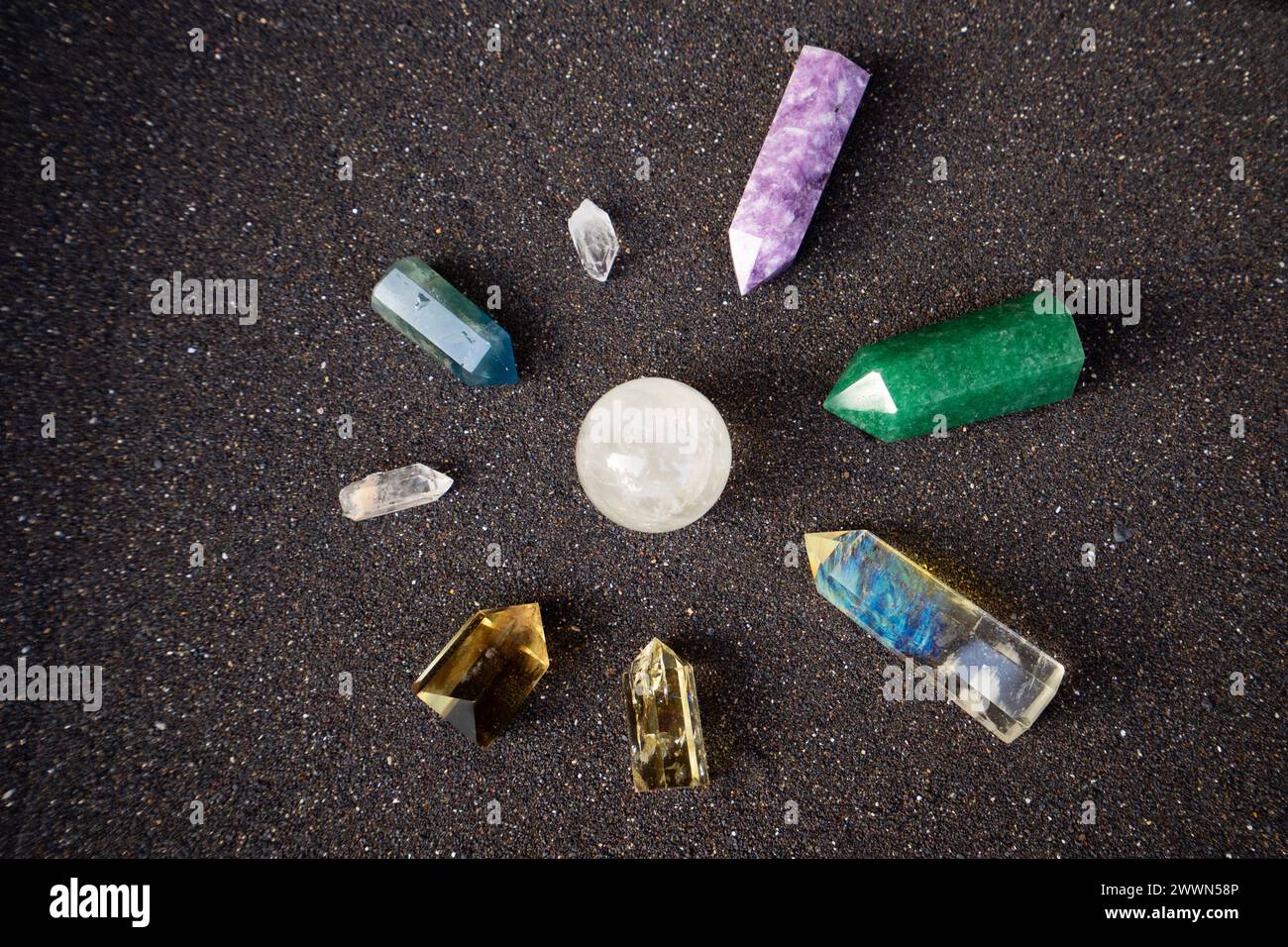 Healing crystals on black sand background Stock Photo - Alamy