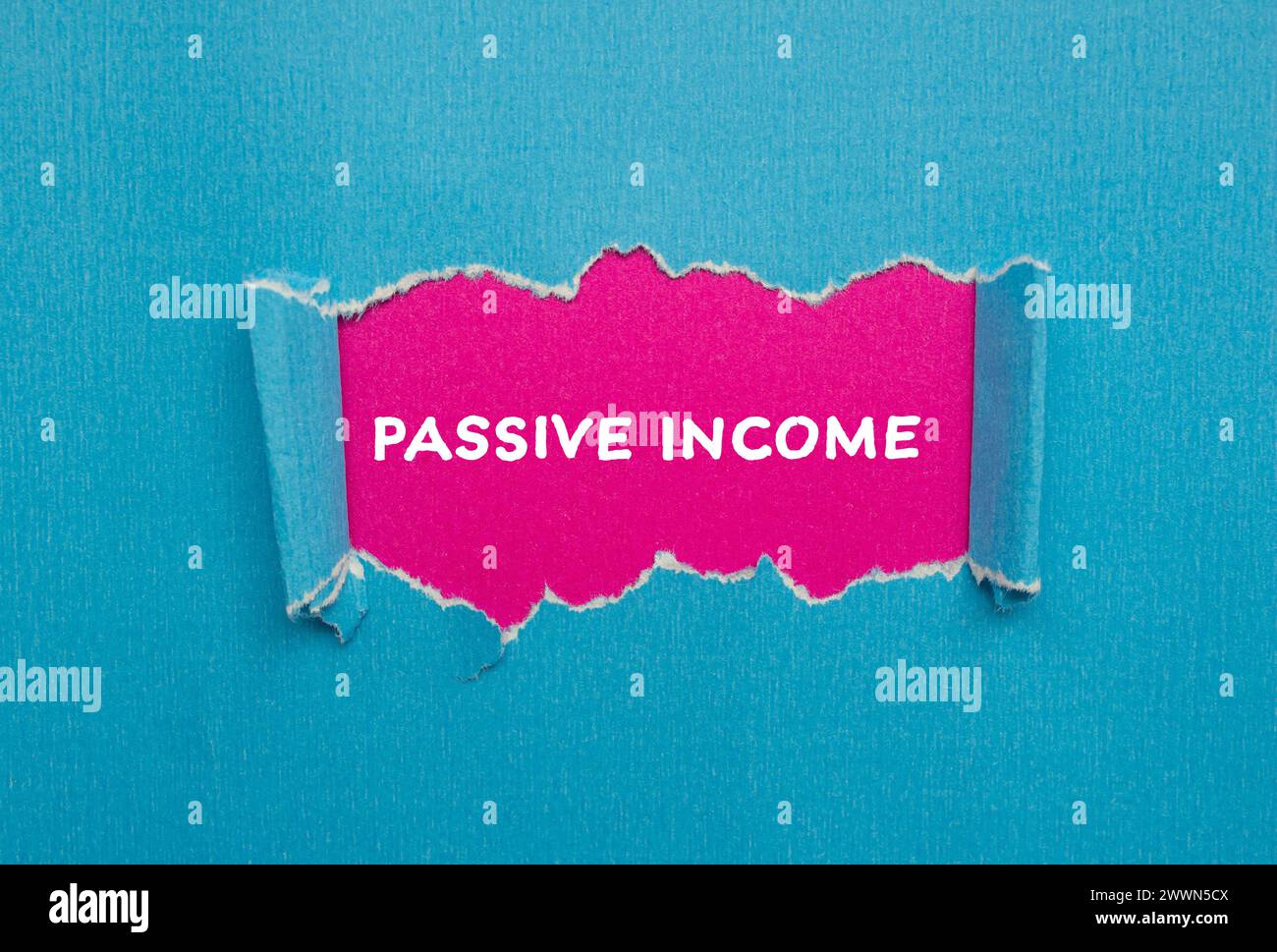 Passive income words written on blue torn paper with pink background ...