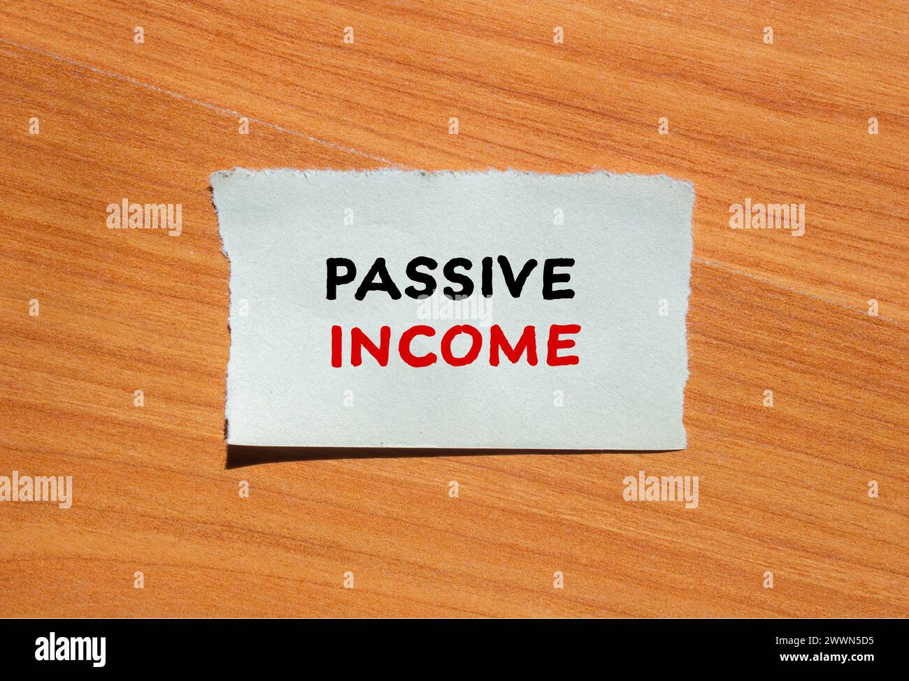 Passive income words written on torn paper piece with wooden background ...