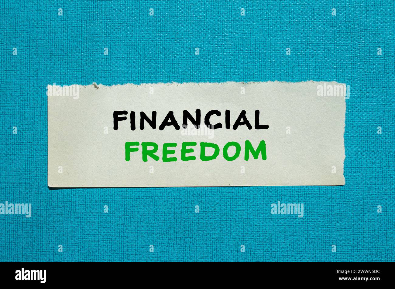 Financial freedom words written on torn paper piece with blue ...
