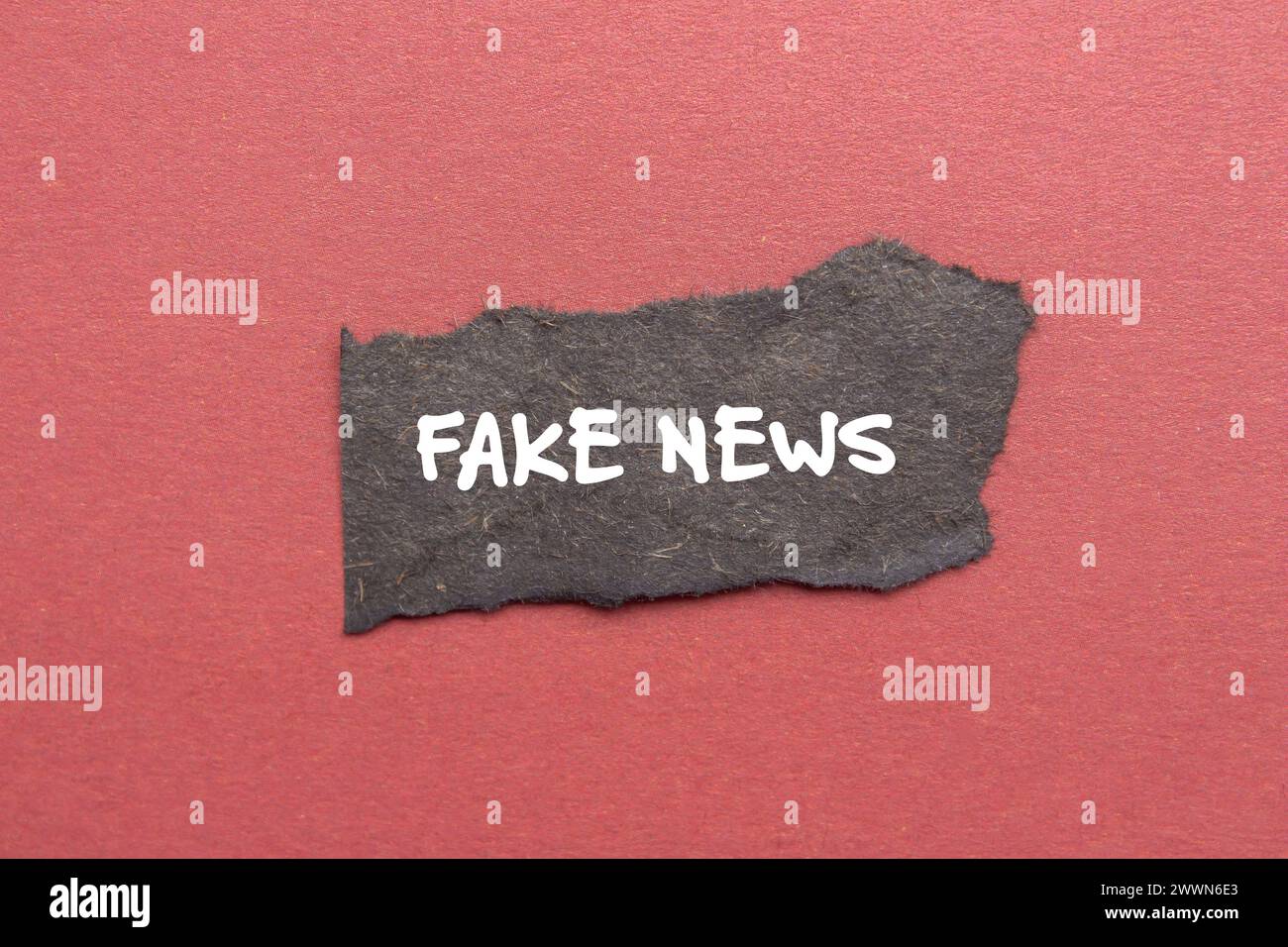 Fake news words written on black torn paper piece with red background ...