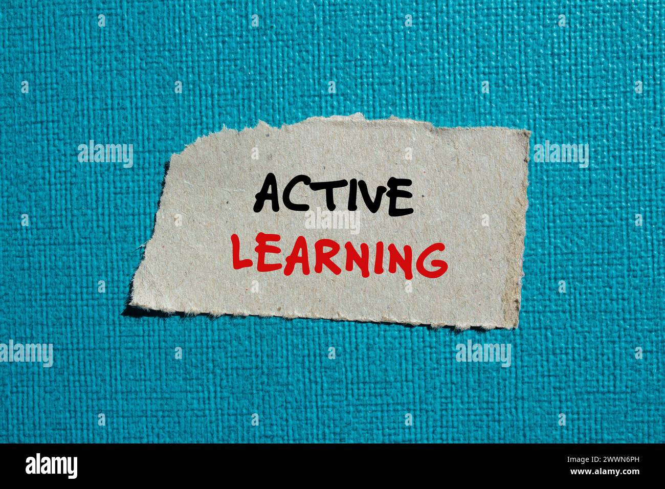 Active learning words written on torn paper piece with blue background ...