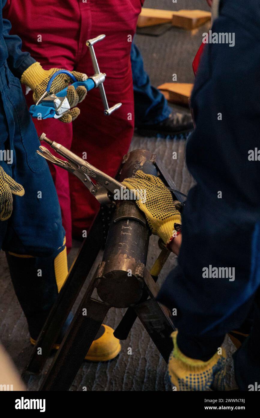 Sailors conduct pipe patching drills in the hangar bay of Nimitz-class ...