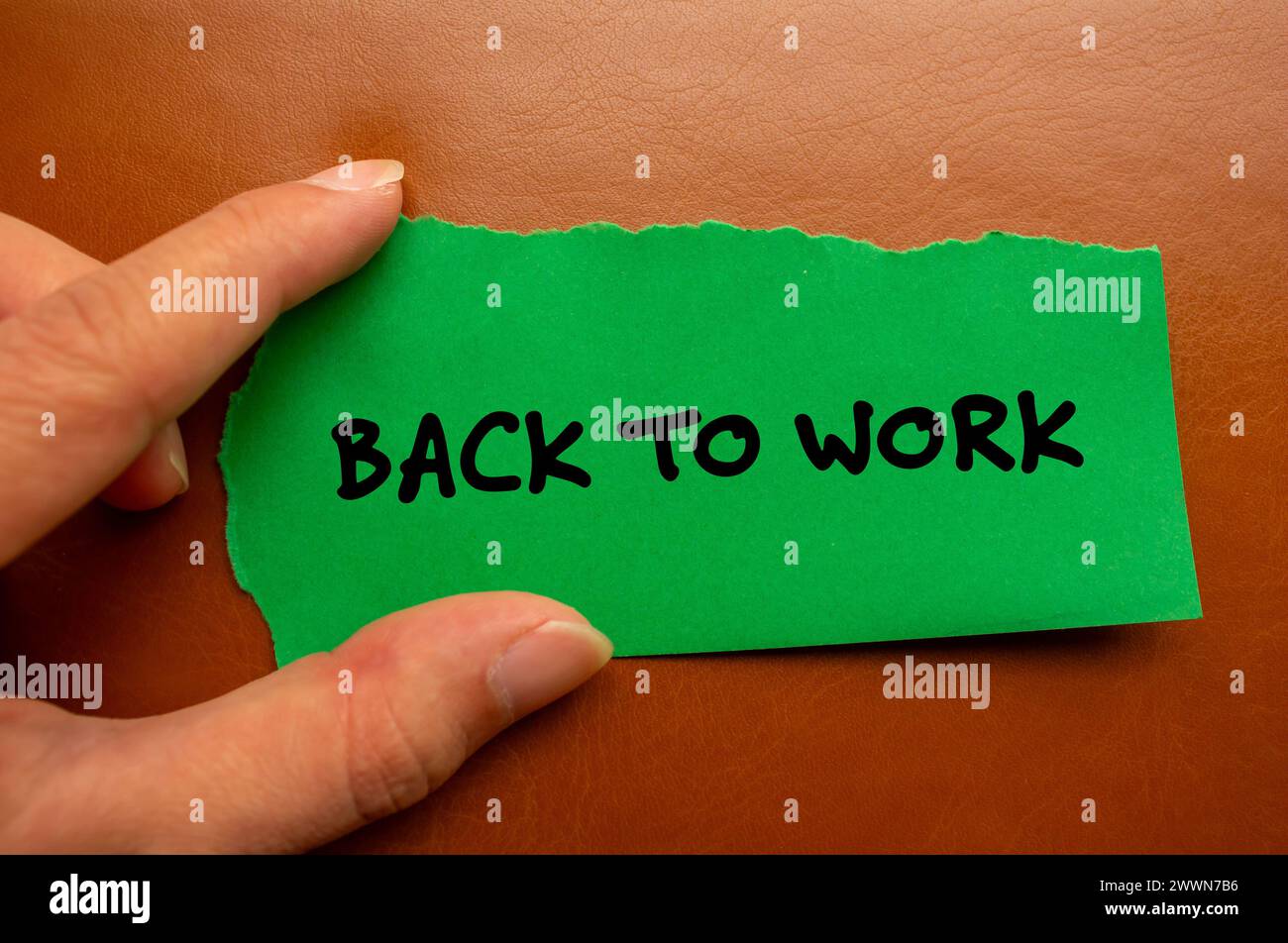 Back to work words written on green torn paper piece with brown background. Conceptual business ...