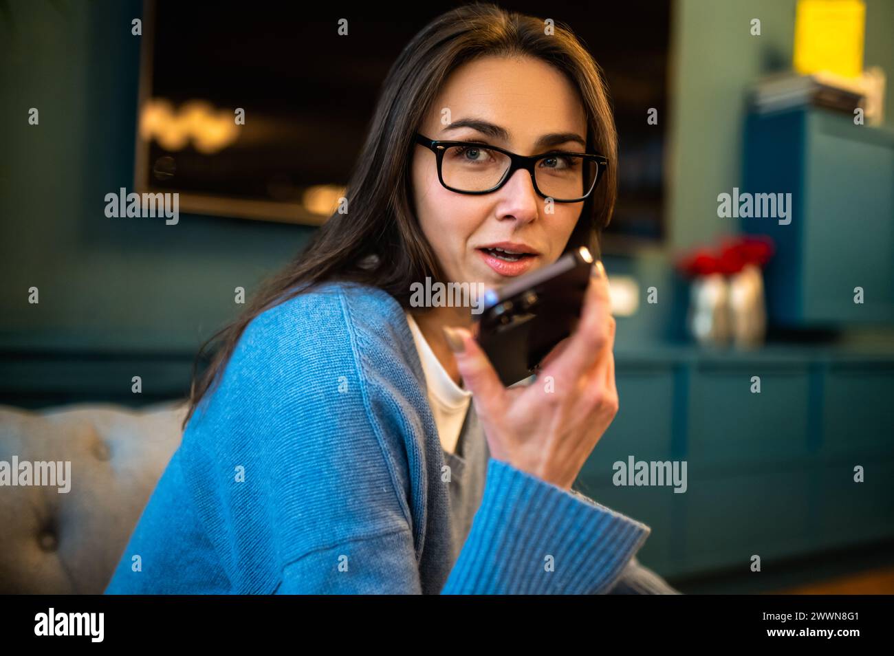 Woman wear using mobile phone for recording voice message in hotel room ...