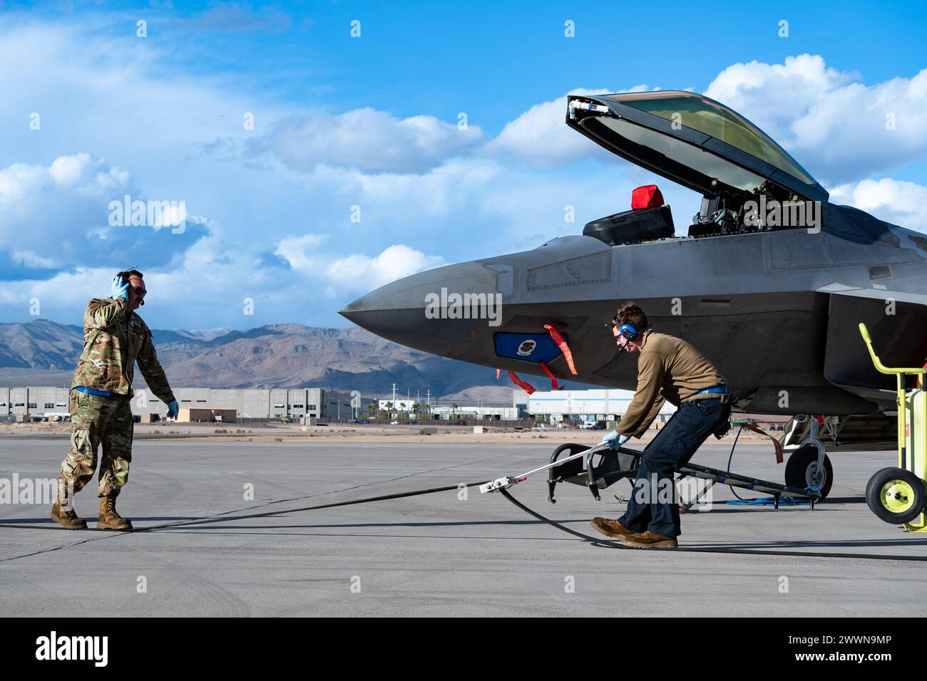 Two U.S. Air Force Airmen pull a squeegee to defuel the hose back into ...