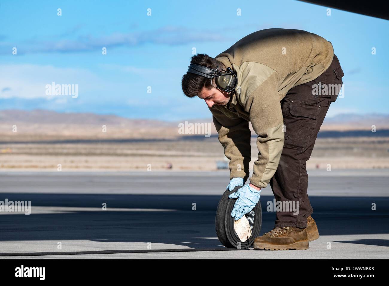A U.S. Air Force Airman rolls up a fuel hose after refueling an F-22 ...