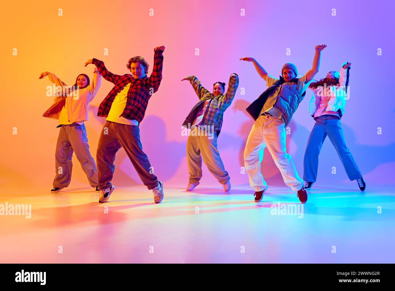 Synchronized movements. Group of young people dancing contemp against ...