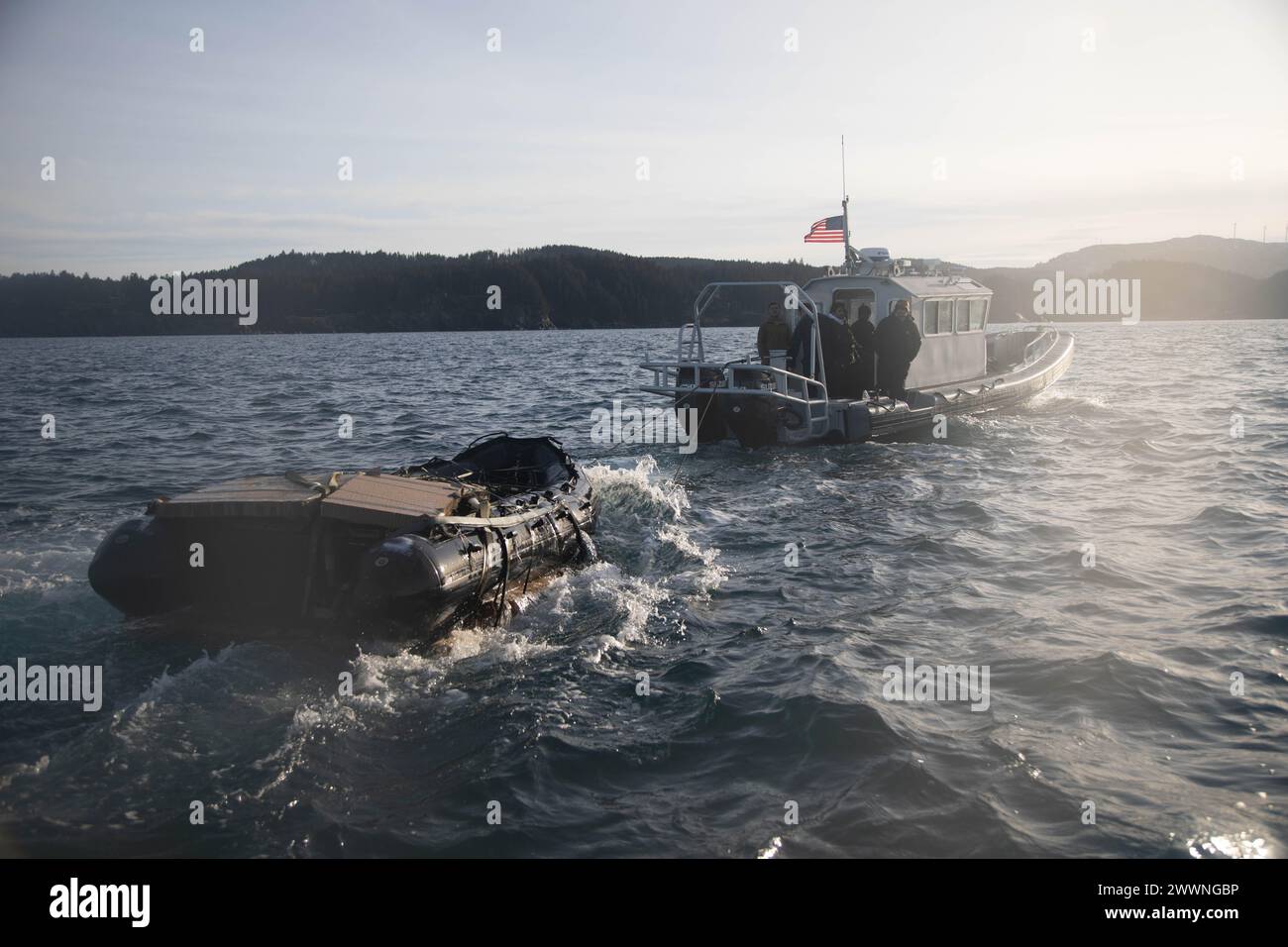 A U.S. Coast Guard vessel sails to shore pulling a Combat Raiding ...