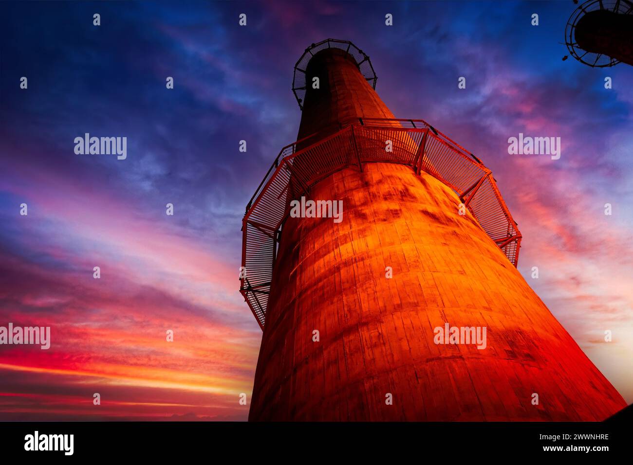 A tall red tower illuminated at dusk against a red sky Stock Photo - Alamy