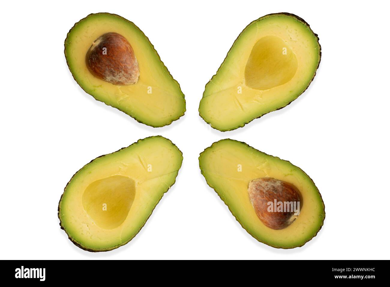 Four avocado halves, two with seed, arranged diagonally, on a white ...