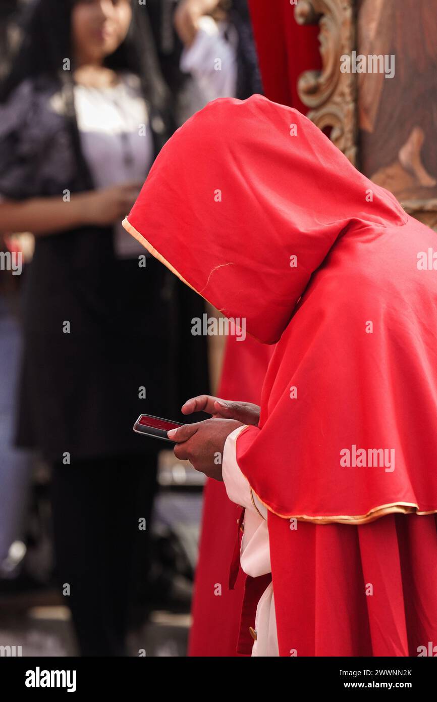 Antigua, Guatemala. 24th Mar, 2024. A Catholic penitent view his mobile ...