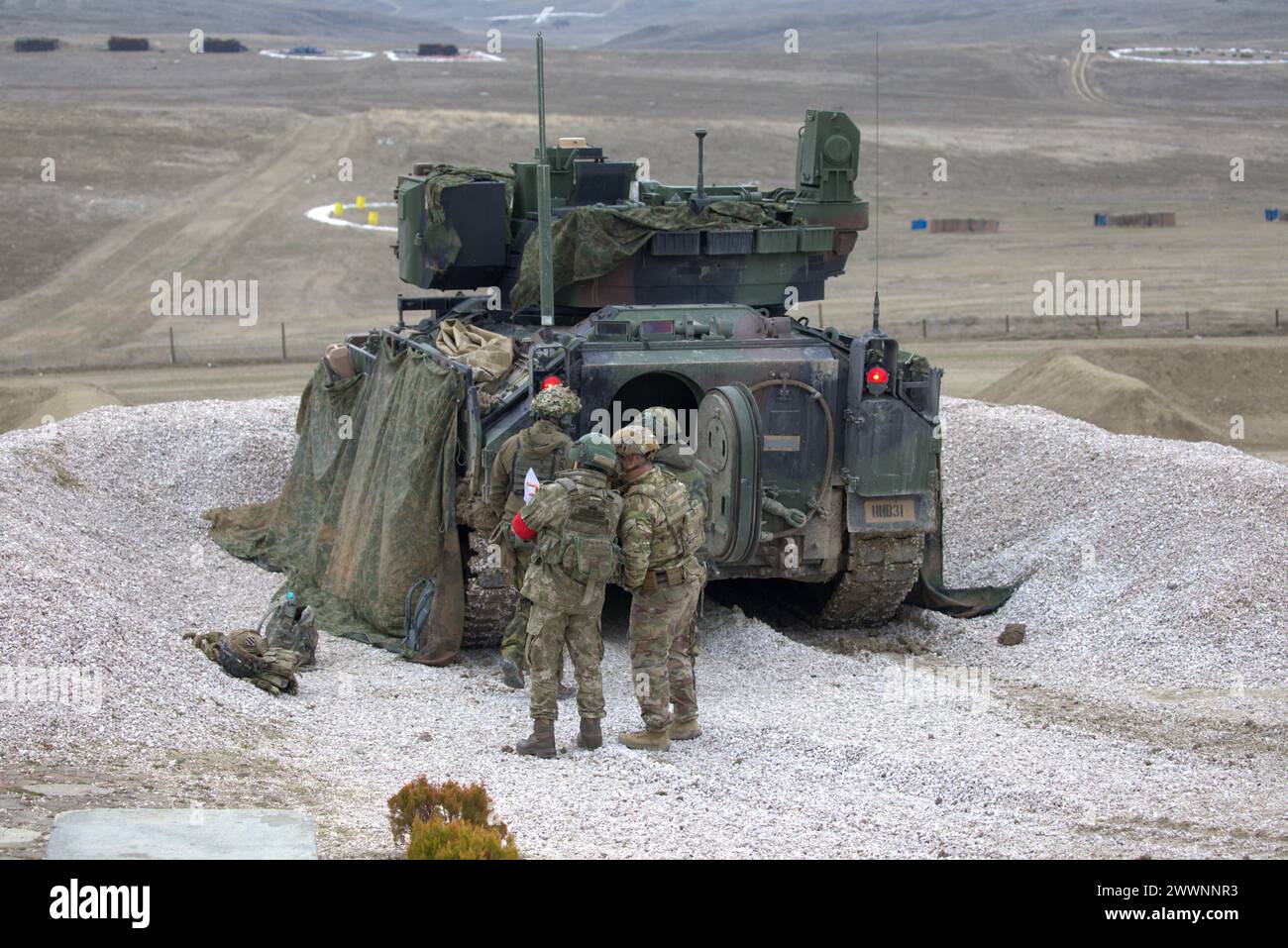 U.S., Czech Republic, and Turkish soldiers stand beside a Bradley Fire ...