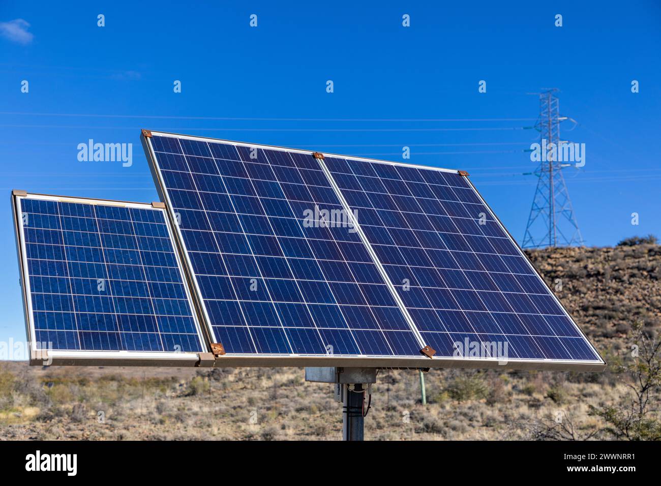 Close up on three solar panels on a make shift frame in an arid area ...