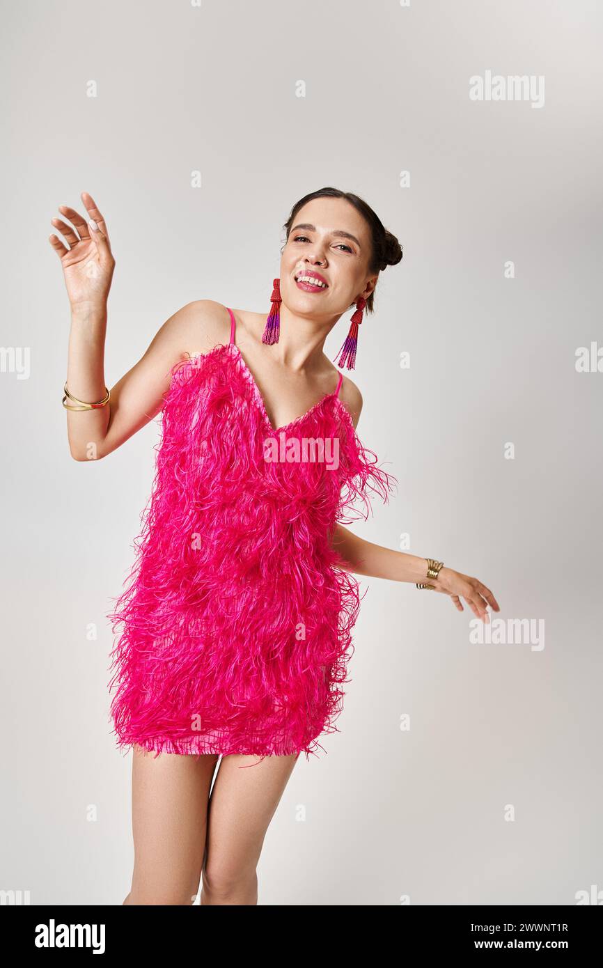 Pretty woman in trendy pink dress and fancy jewelry dancing joyfully on ...