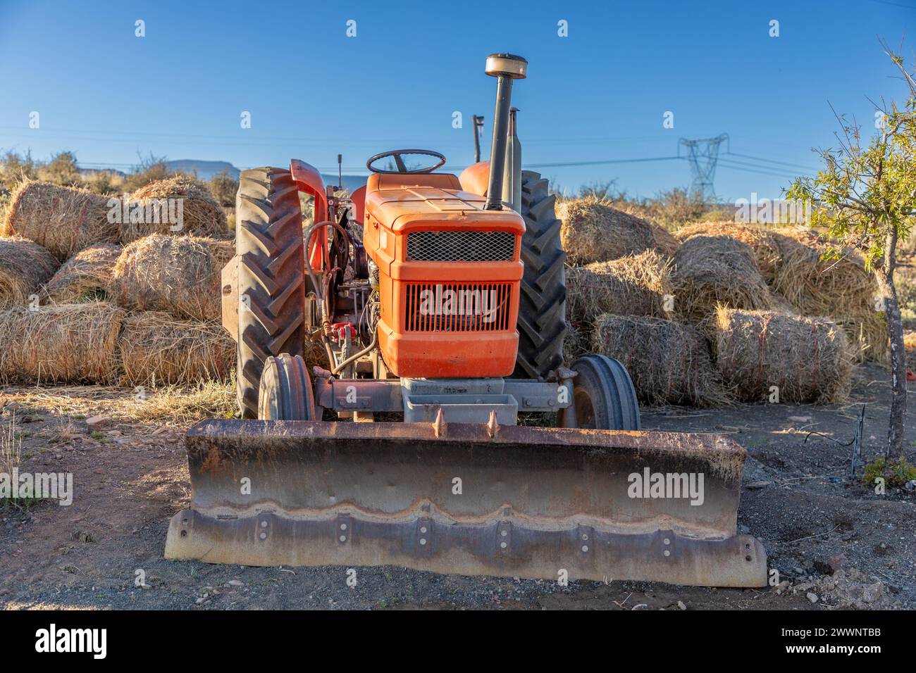 Old tractor in a field with a scraper attached to it. Behind the ...