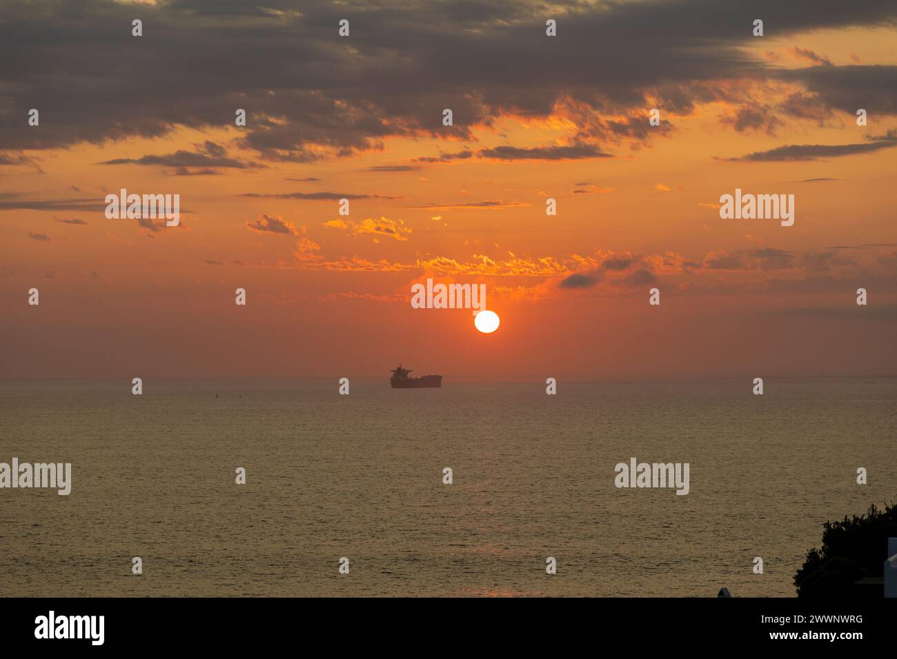 Ship on the ocean during a glowing sunset with a hot burning sun and ...