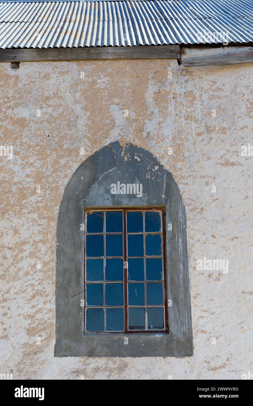 Gothic arch window in an old and abandoned building with a corrugated ...