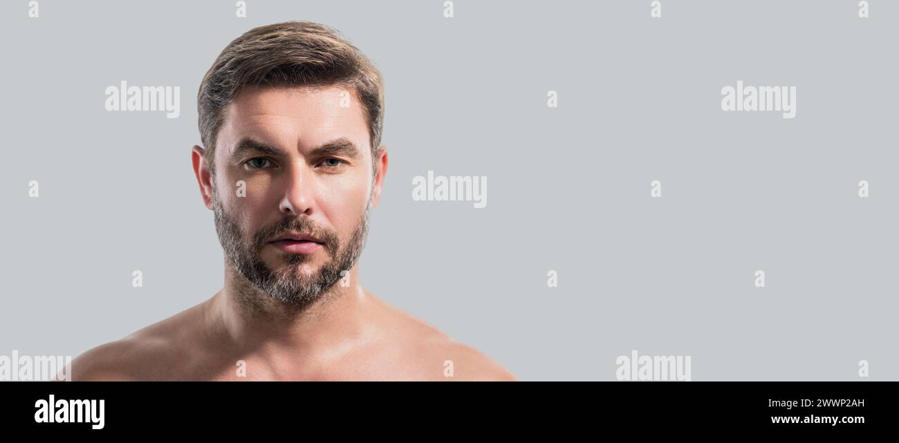 Close up beauty portrait of satisfied man after facial cream. Attractive brunet guy touching ...