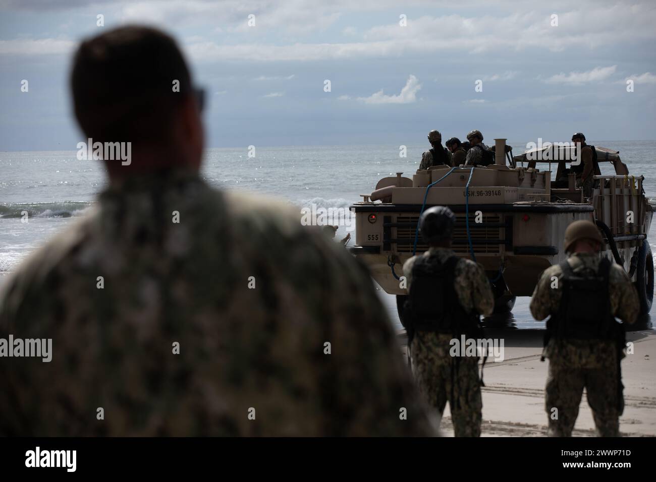 U.S. Sailors, assigned to Beachmaster Unit 1, ground guide a vehicle ...