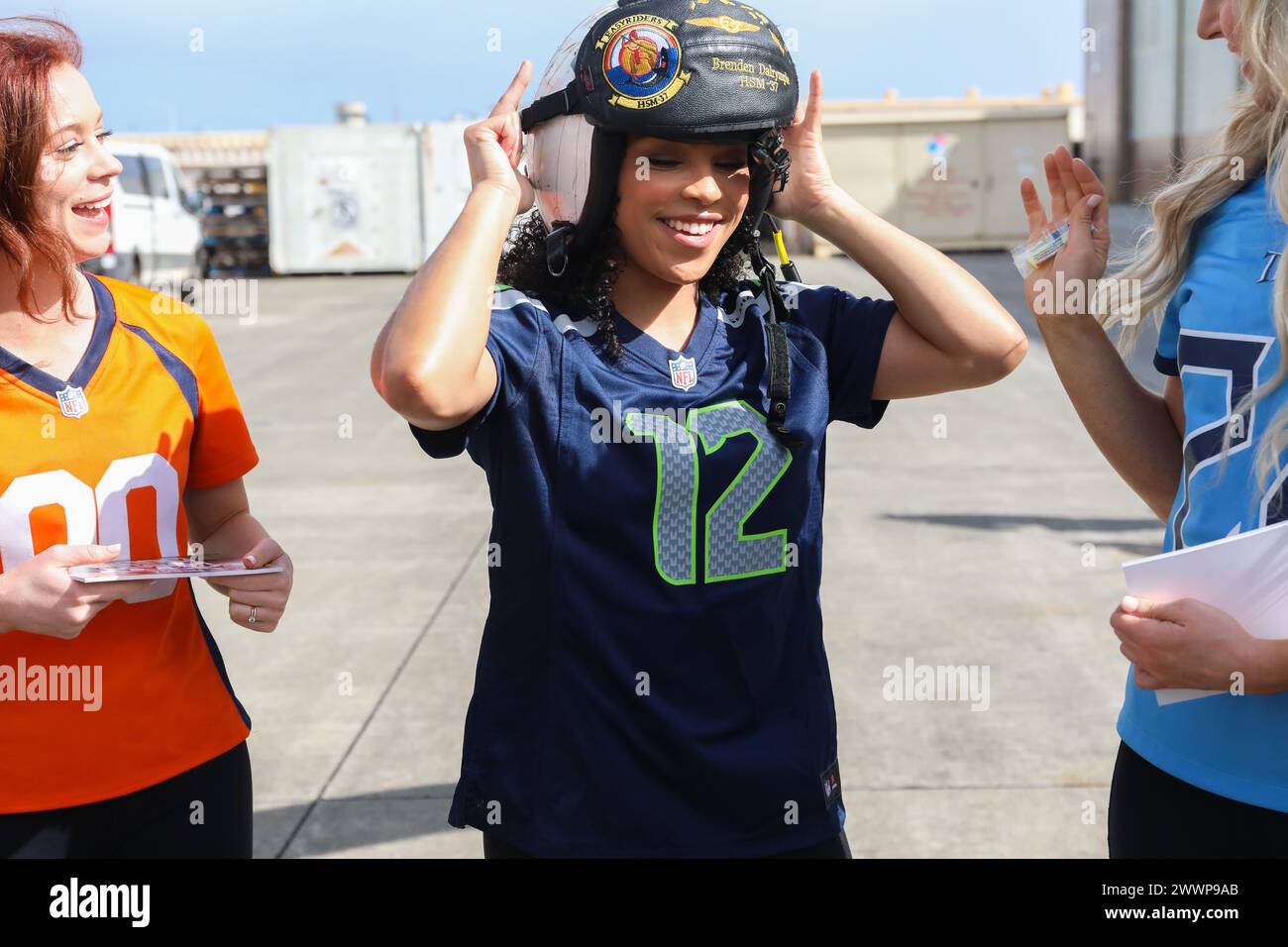 NFL cheerleader Geena Rojas dons a flight deck helmet during the Armed ...