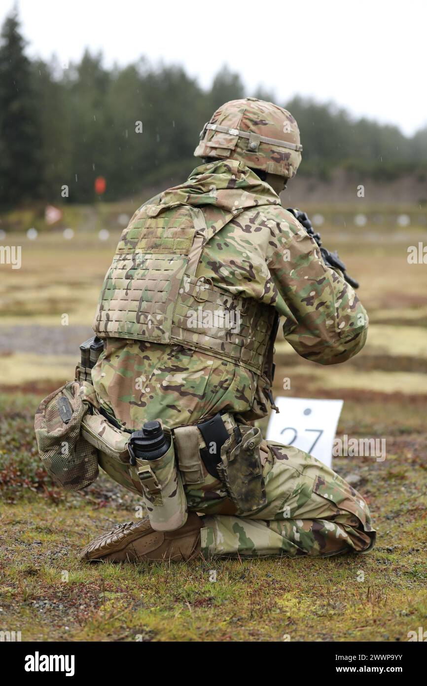 A U.S. Army Soldier takes a kneeling position and fires at a target ...