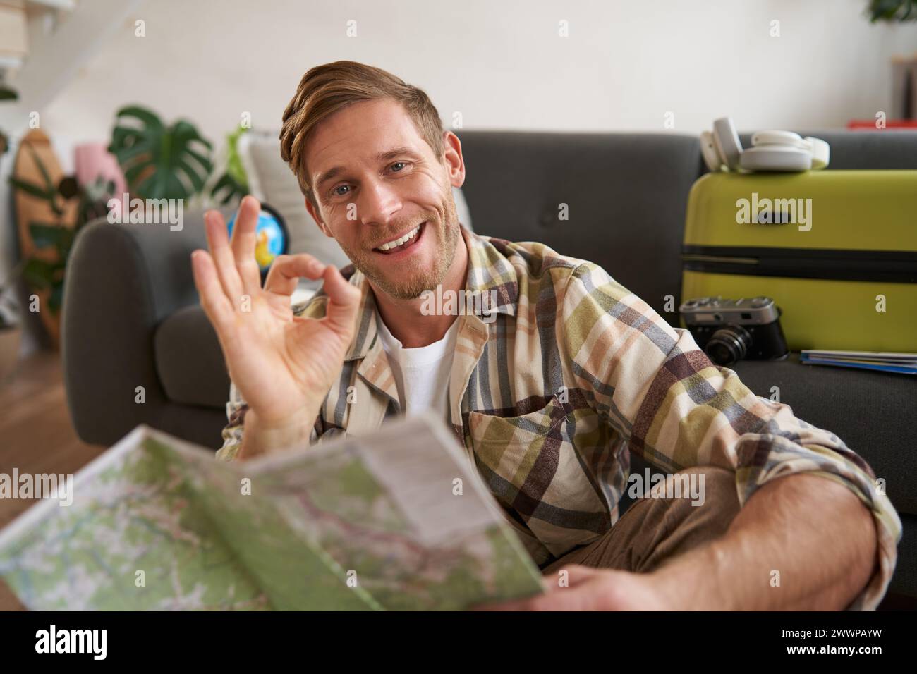 Good-looking guy, tourist with travel map, shows okay, ok sign, approve ...